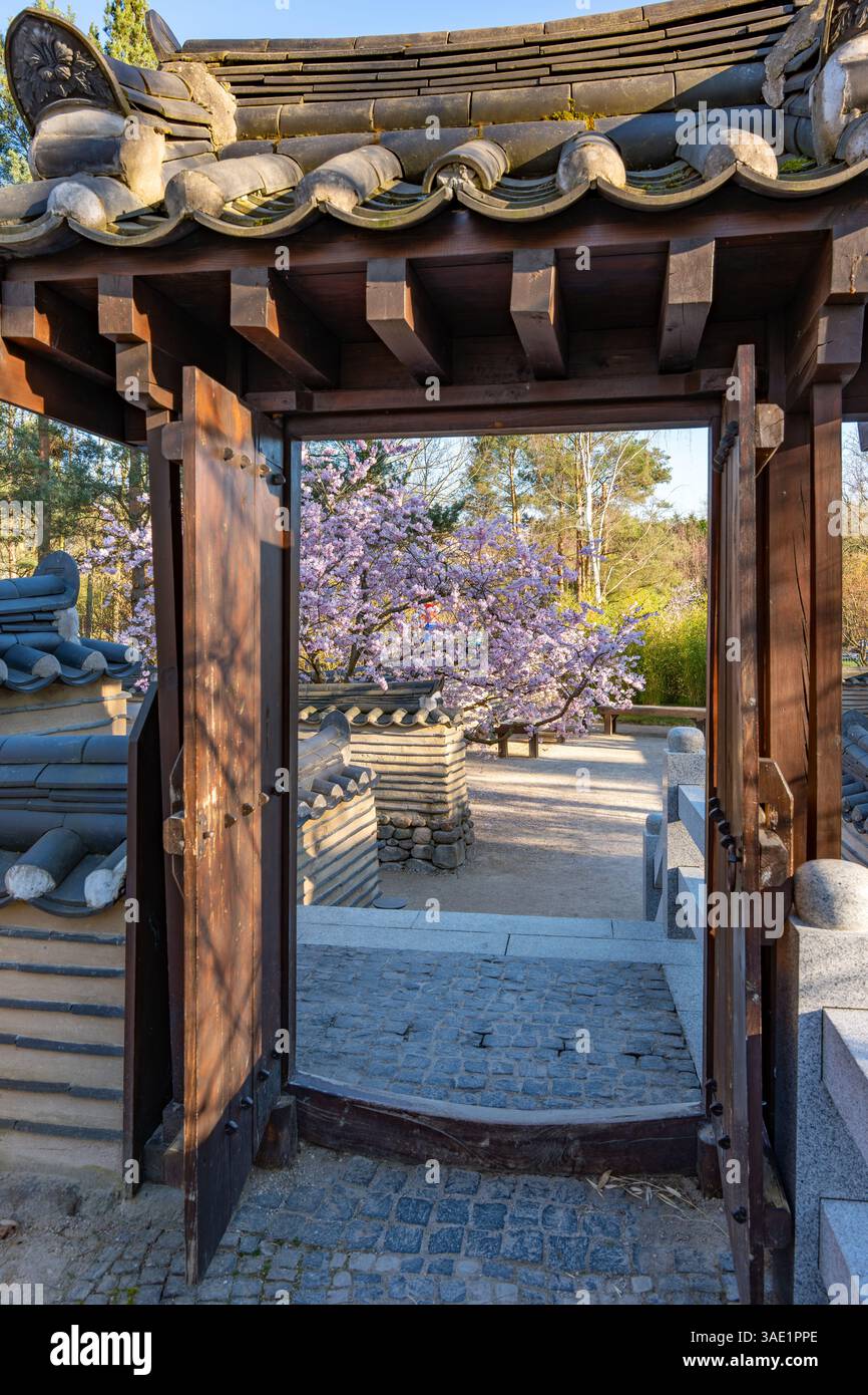 A wooden gate with a door open. The gate is in front of a building ...