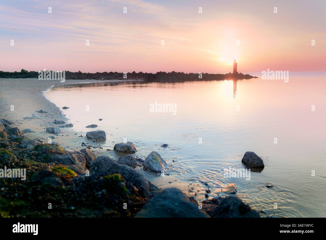 The shoreline, composed of smooth sand and rugged rocks covered in patches of moss, curves ...