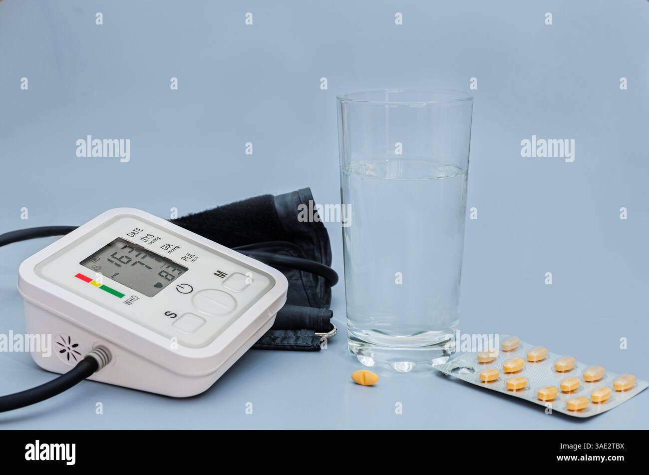 Close-up of a blood pressure monitor, glass of water and blister pack ...