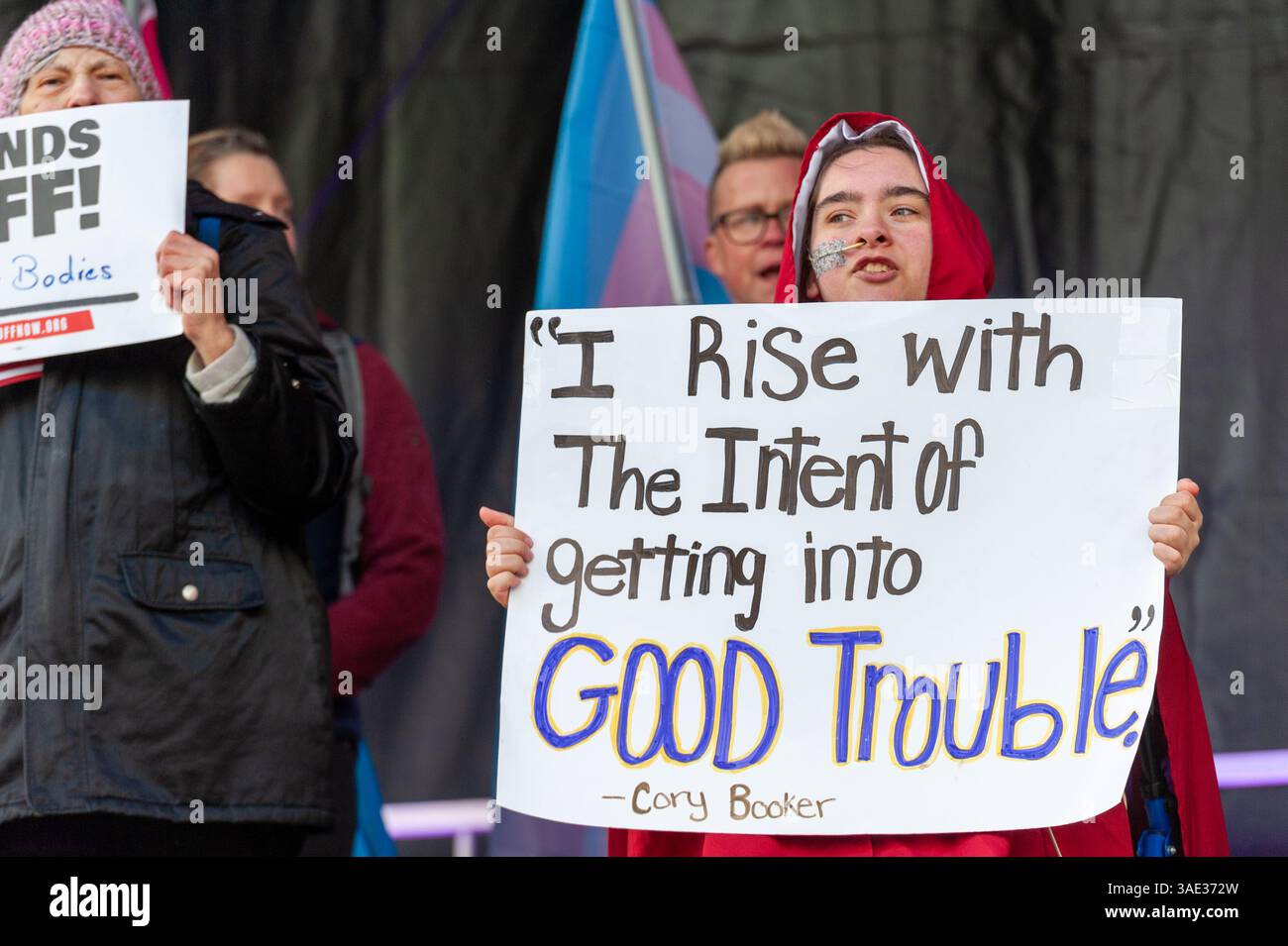 Closeup of girl on stage holding a sign with "I Rise with The Intent of ...
