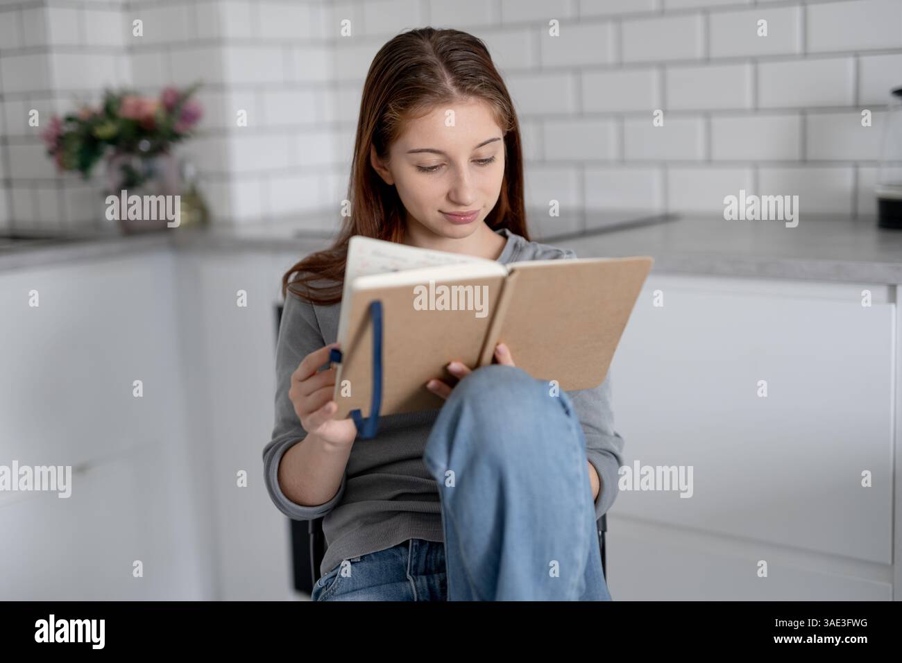 Sweet Teen Girl Reading Notebook Entries While Sitting On A Chair At ...