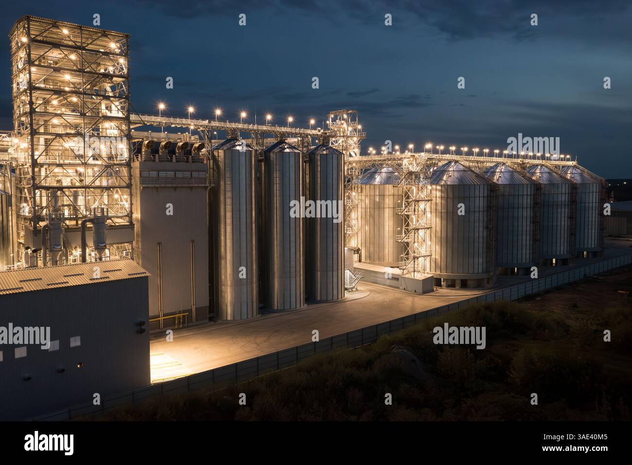 Night aerial view of illuminated grain elevator and silos. Modern grain ...