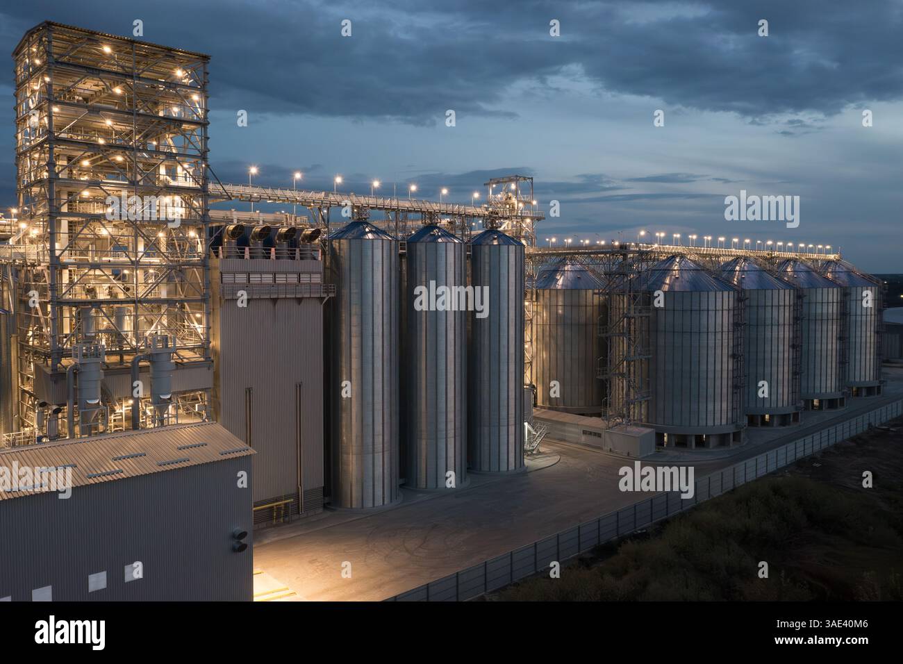 Aerial night view of illuminated grain silos and grain elevator facility in countryside, modern ...