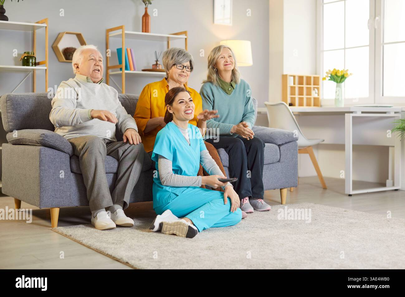 Happy senior people watching TV sitting on sofa in retirement home with ...