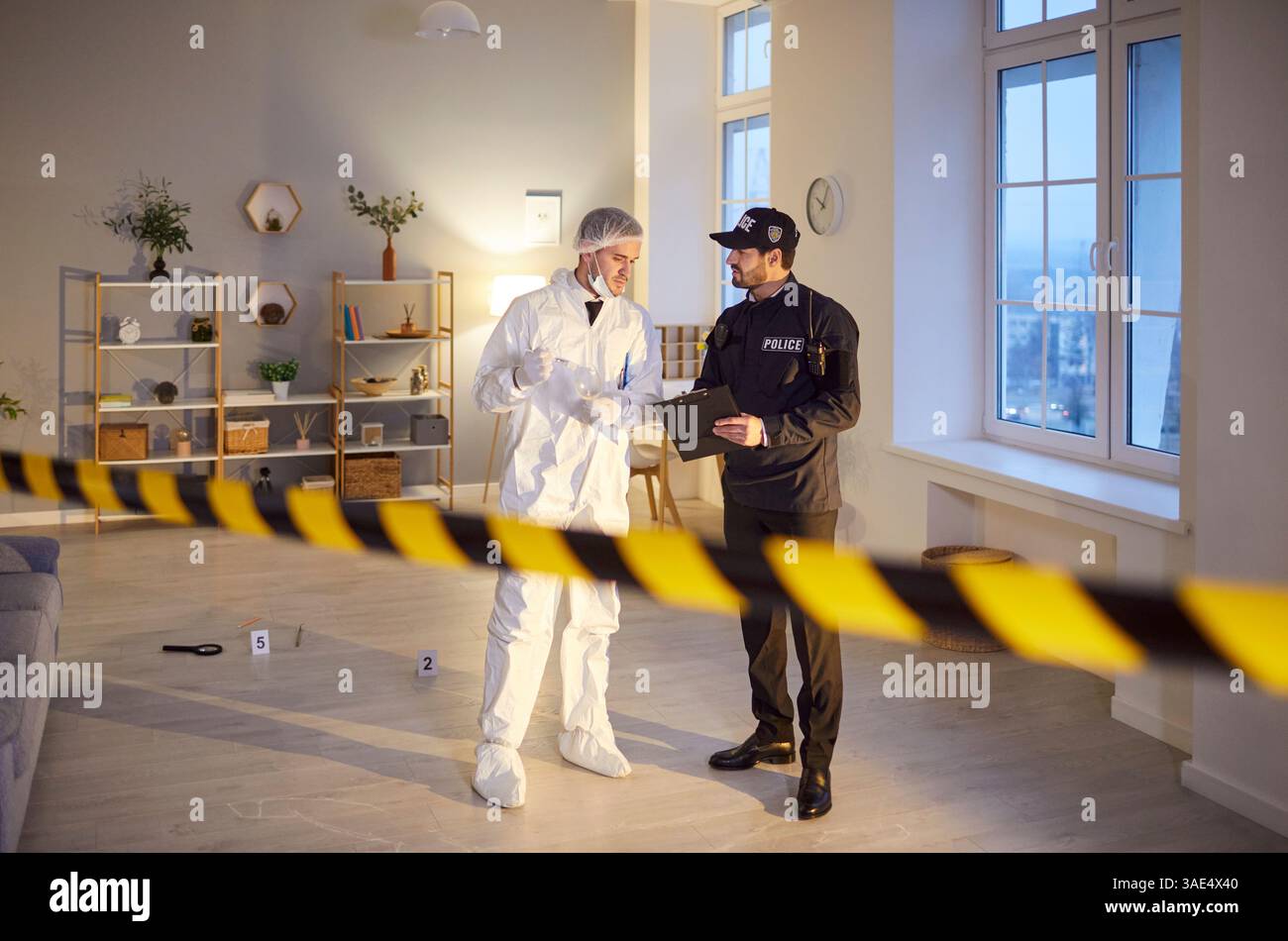 Male police officer in uniform standing at fenced crime scene with ...