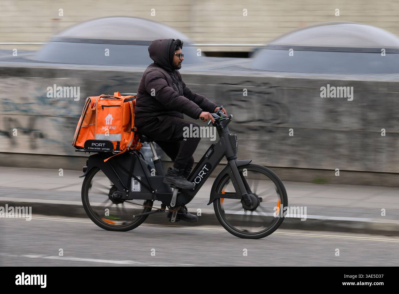 A Just Eat cycle courier riding an e-bike across Waterloo Bridge ...