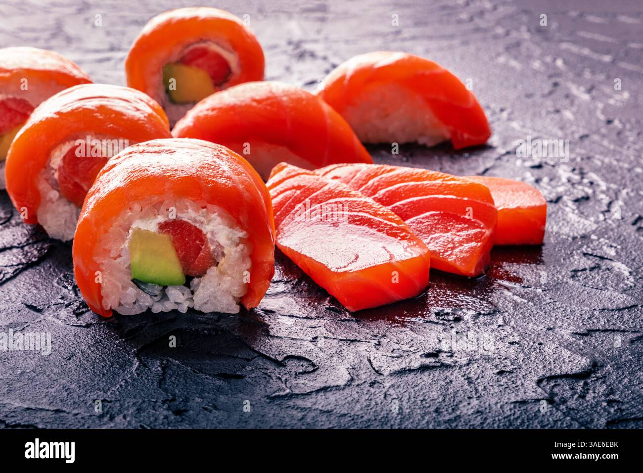 Salmon uramaki sushi roll set, sashimi slices, and nigiri on a black ...