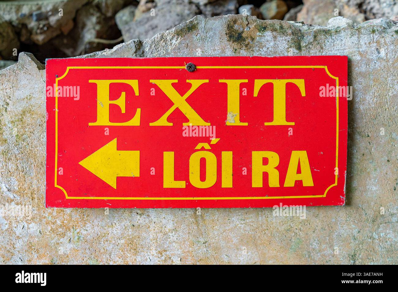 A close-up shows a red exit sign with Vietnamese translation, mounted ...