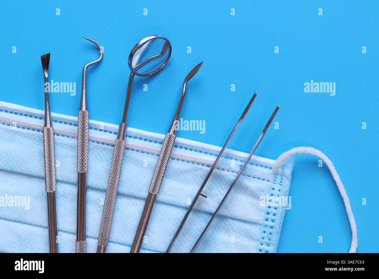Dental mirror, tweezers and several hooks on disposable medical mask ...
