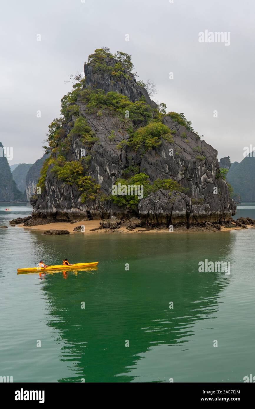 A yellow kayak glides through the tranquil waters of Ha Long Bay ...