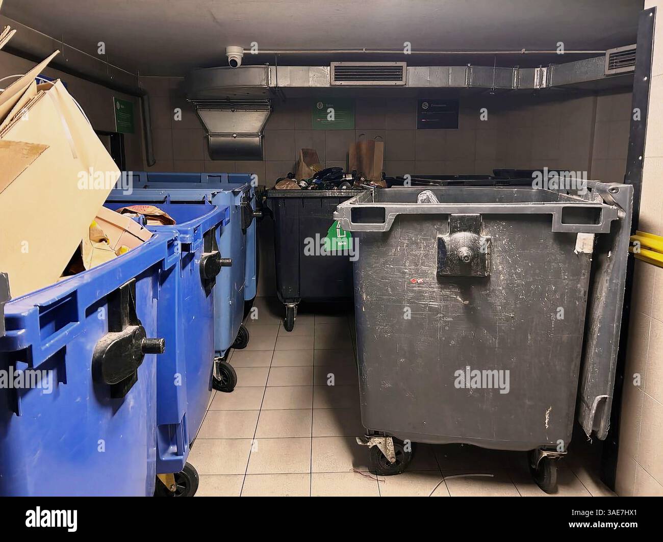Indoor waste sorting station with large bins. A dimly lit indoor waste ...