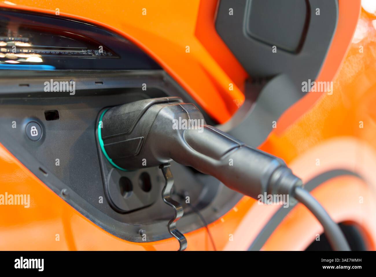 sleek orange electric car plugged in at its rear charging port ...