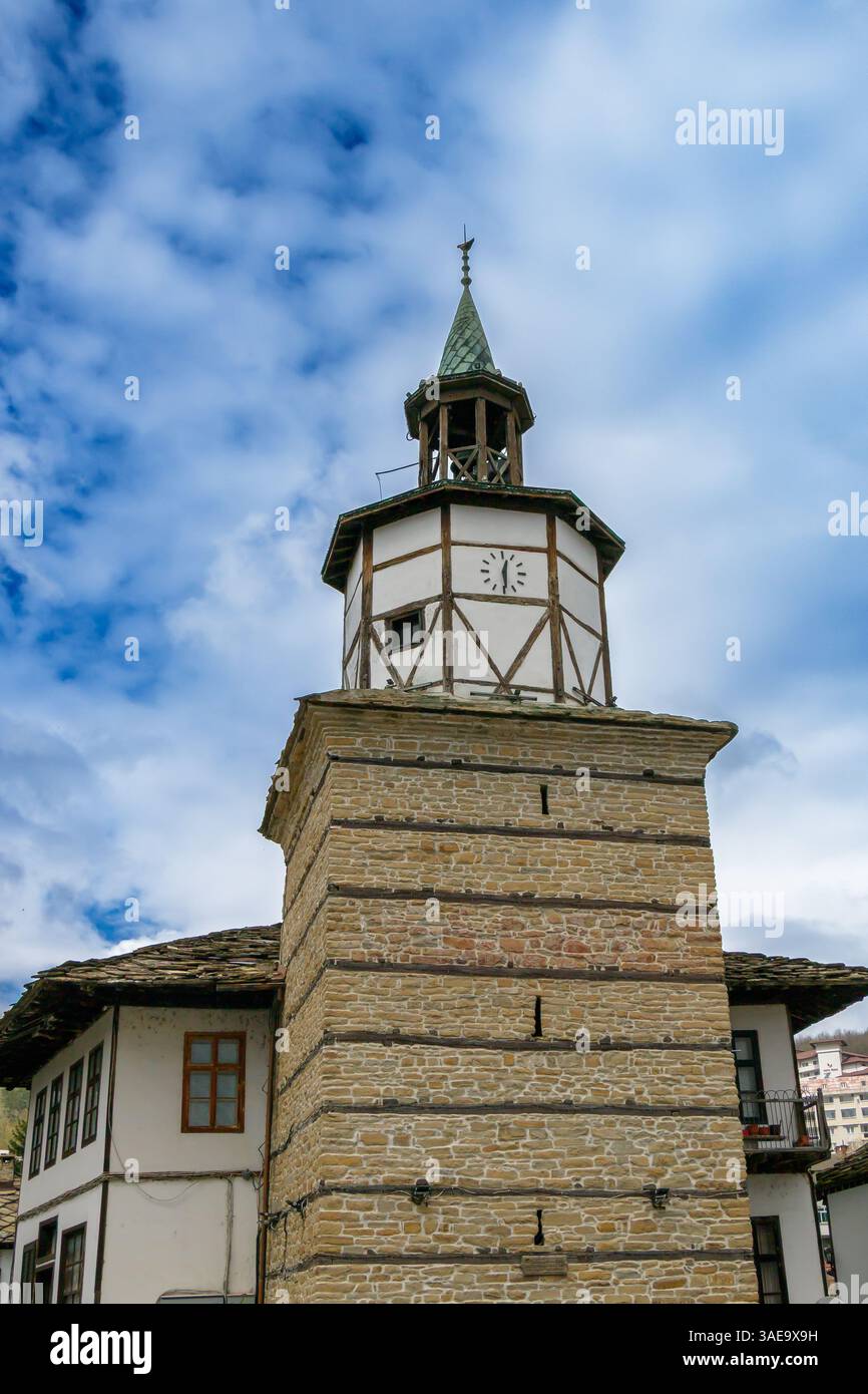 A clock tower rises above a quaint mountain village, showcasing ...