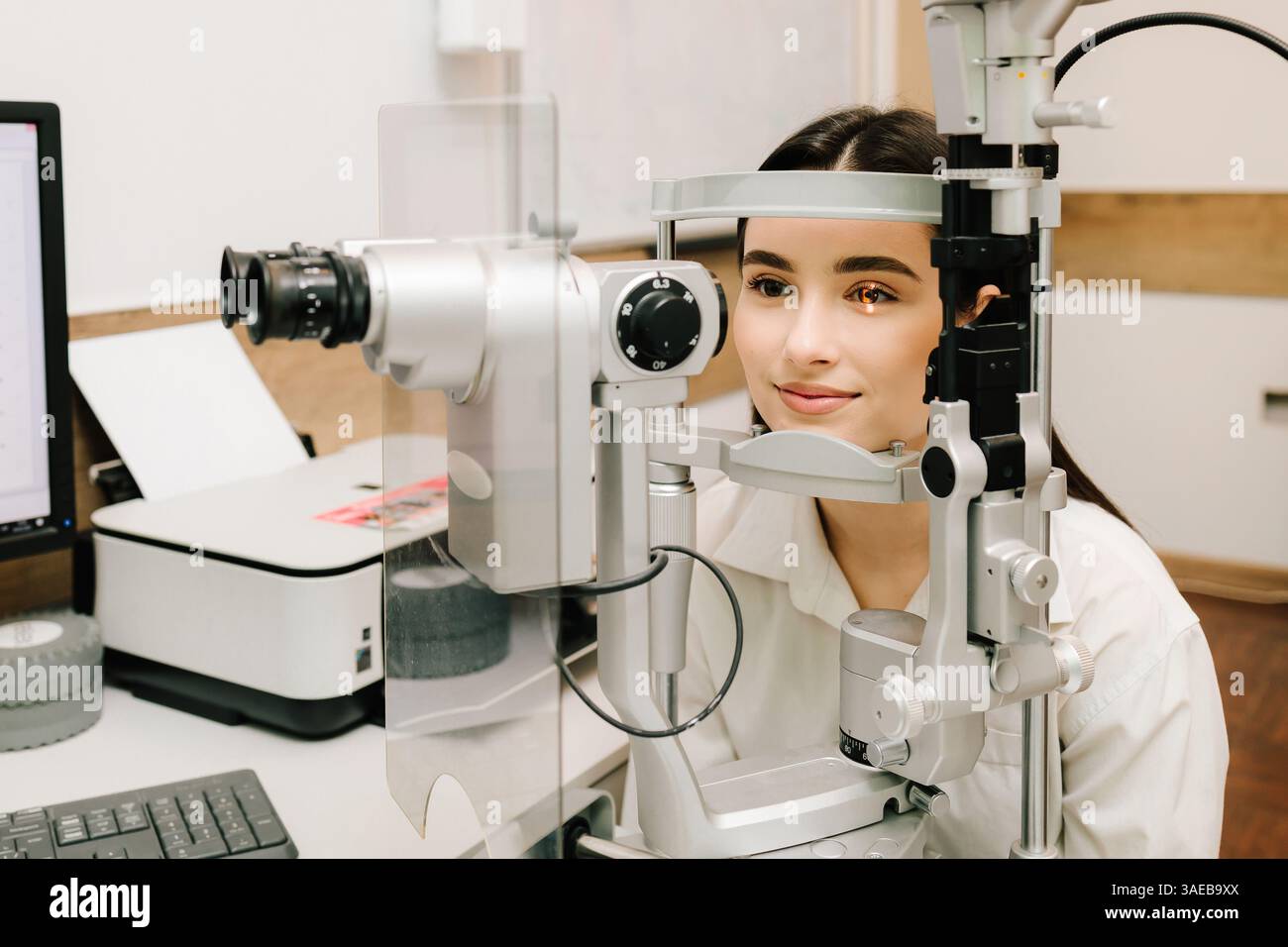 Ophthalmologist illuminates eye of patient with light from slit lamp to ...