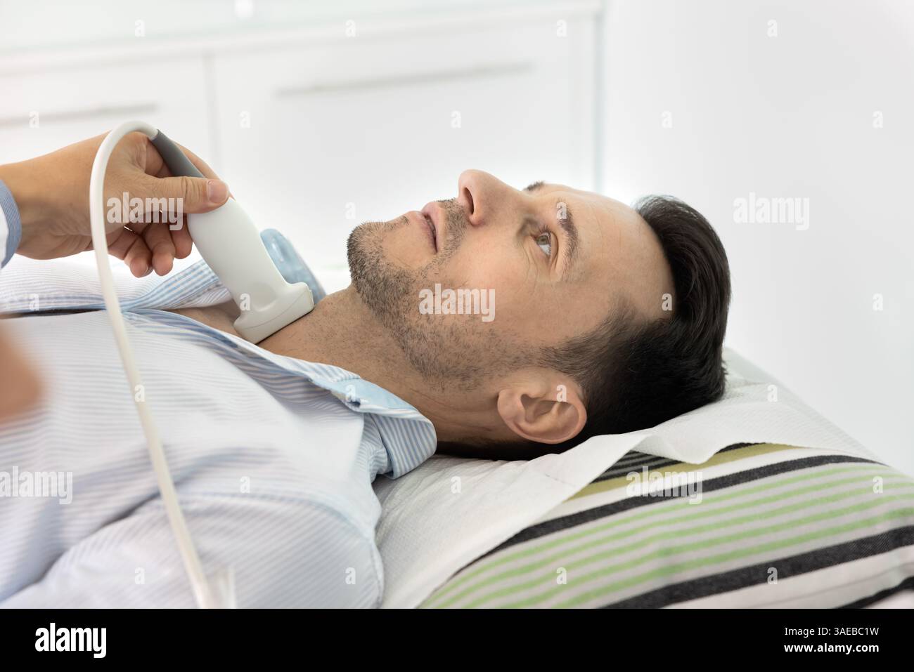 Man lying on examination table during ultrasound scanning procedure ...