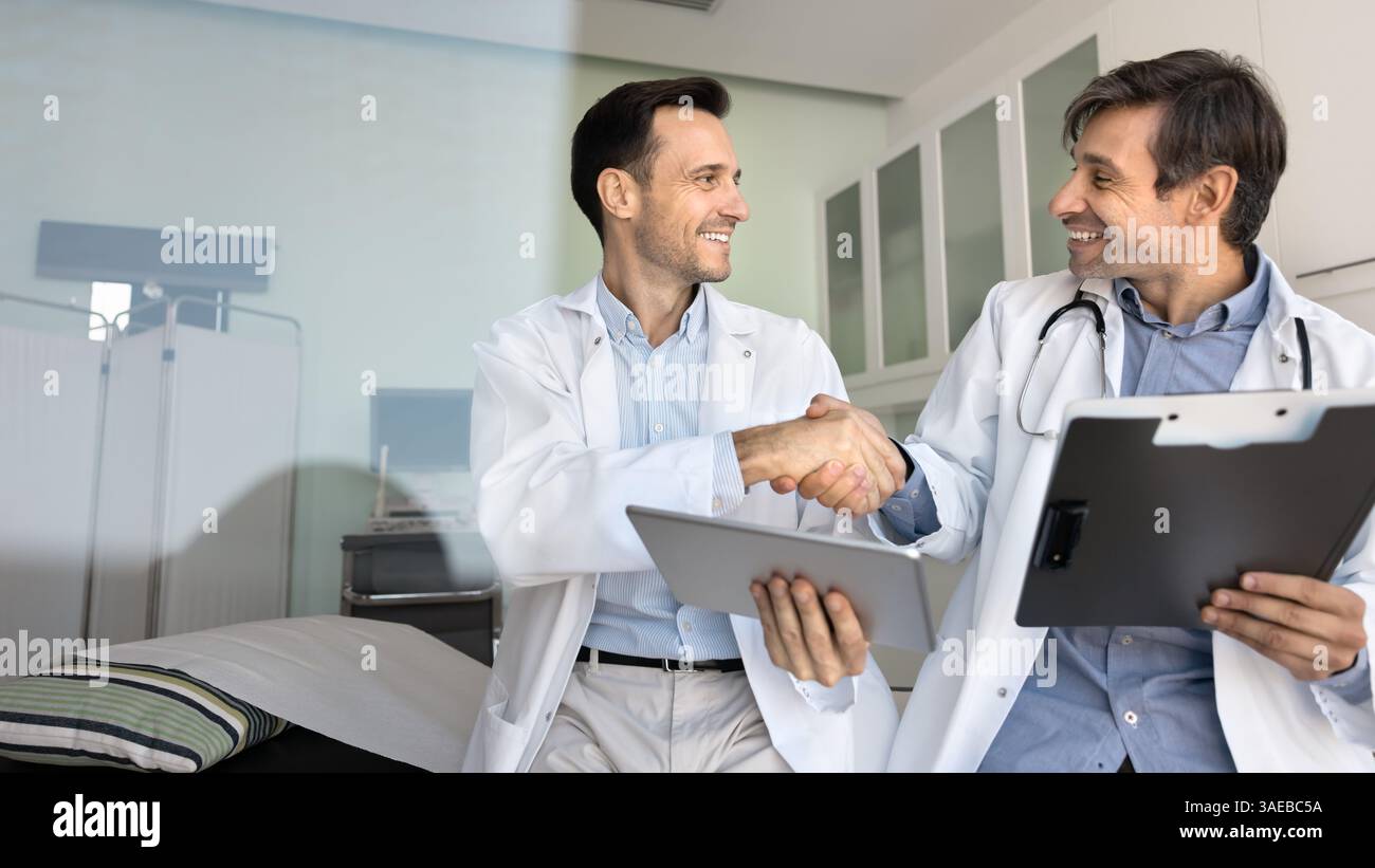Two happy doctors shaking hands during meeting in clinic Stock Photo ...