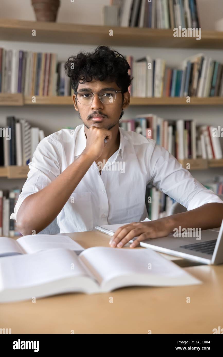 Portrait confident male student sitting at work table in library Stock ...