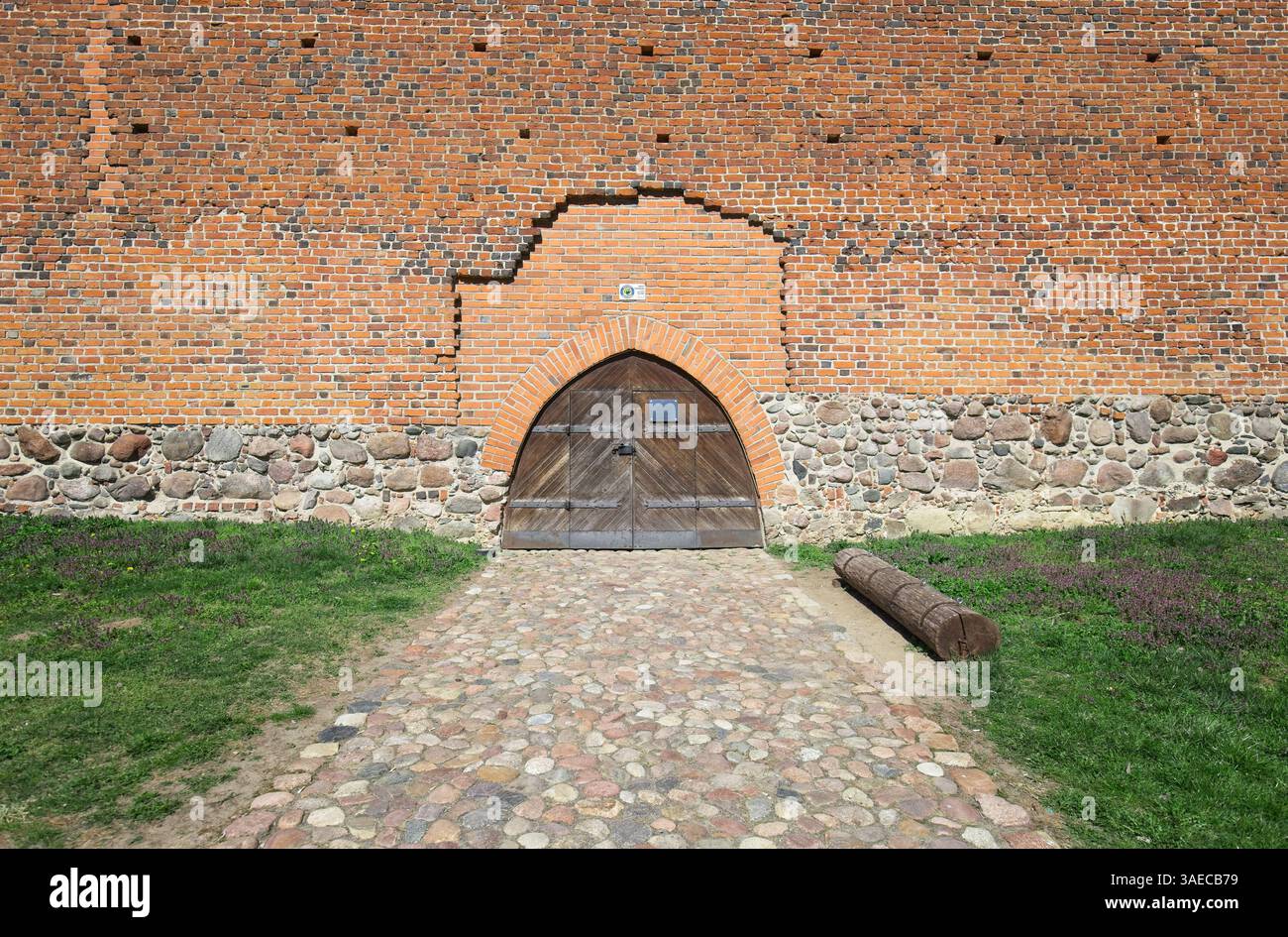 Old brick wall with a wooden arched door, cobblestone path, and stone ...
