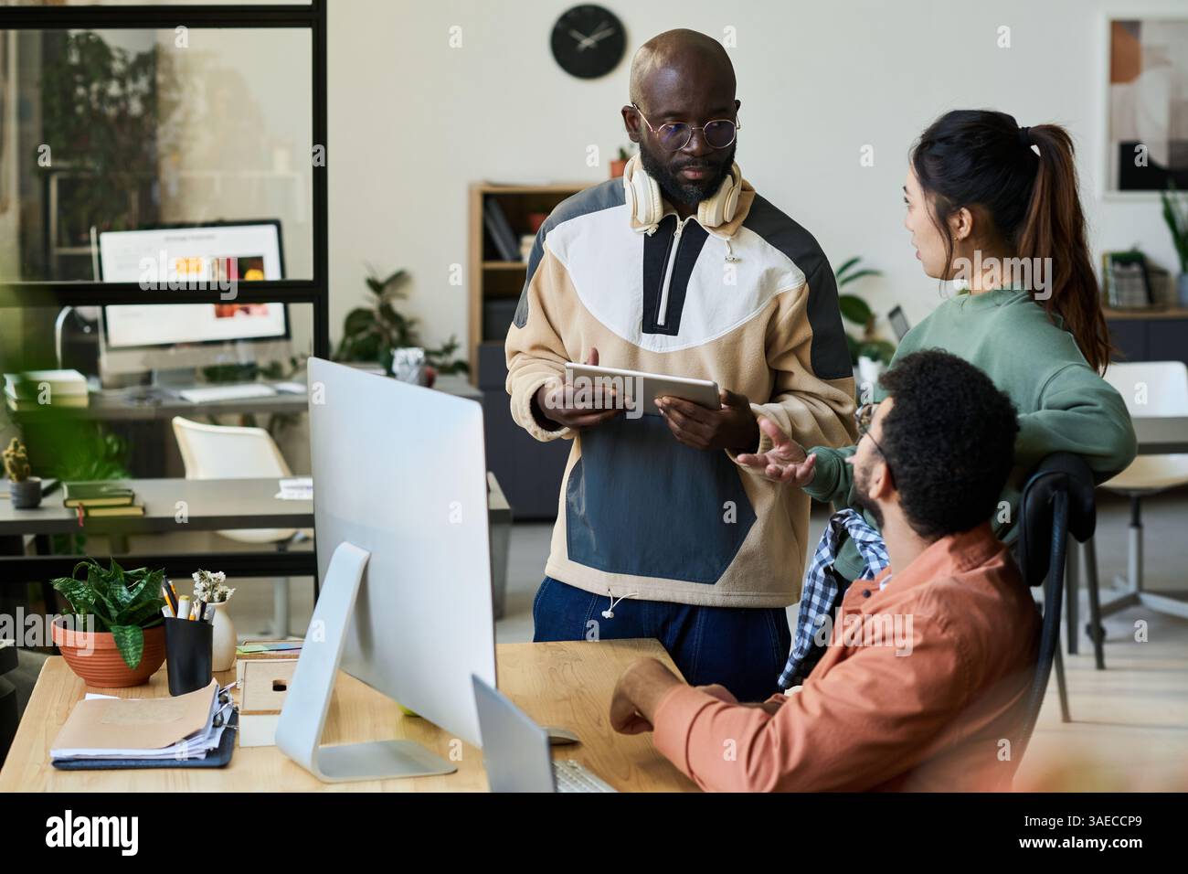 Young serious male programmer with tablet looking at Chinese female ...