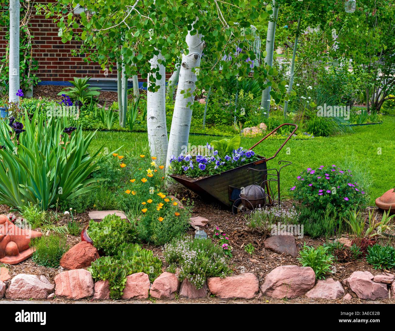 A mixed garden bordered by rocks with decorative elements including a ...