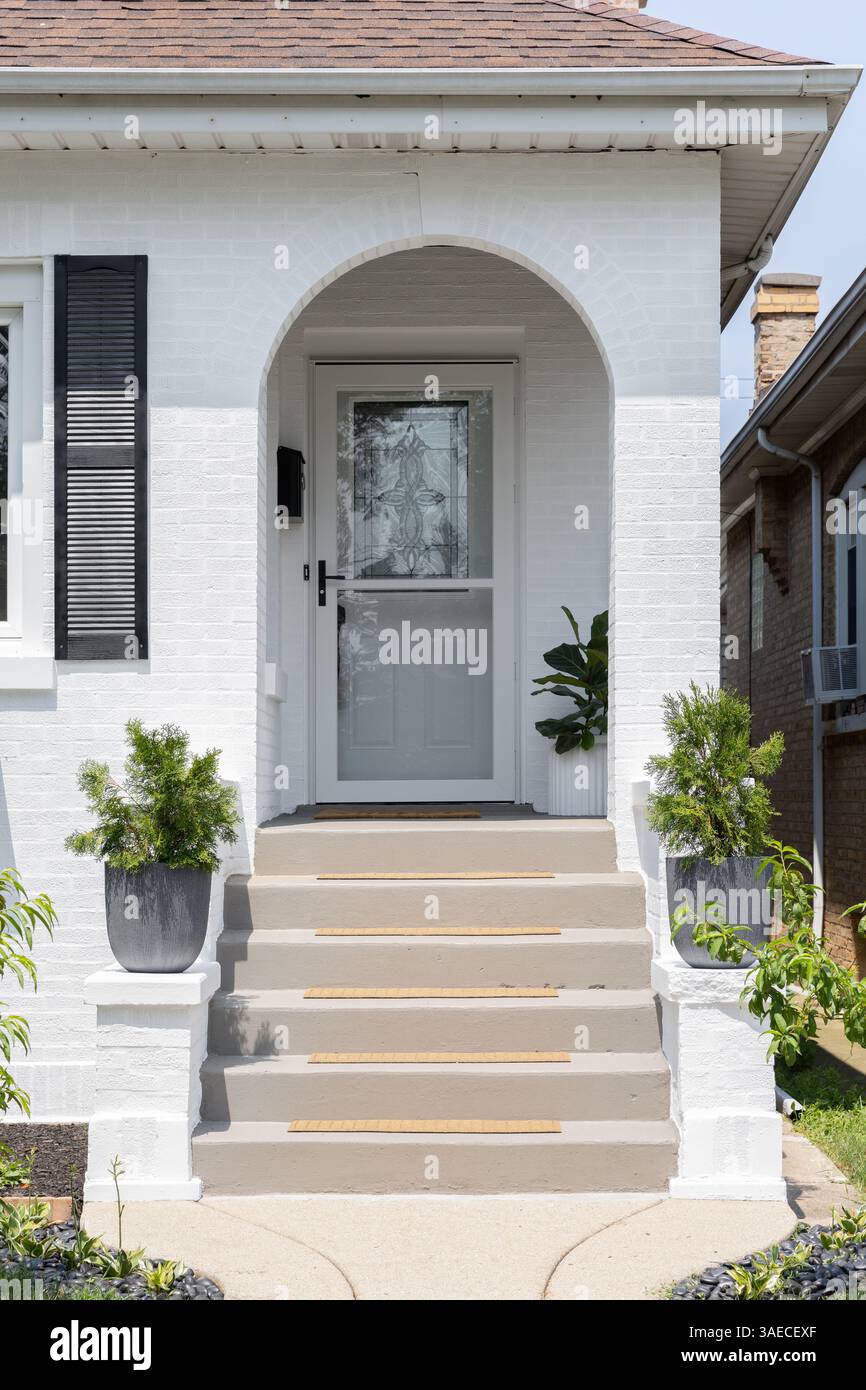 A front door detail with concrete steps leading to an arch covered ...
