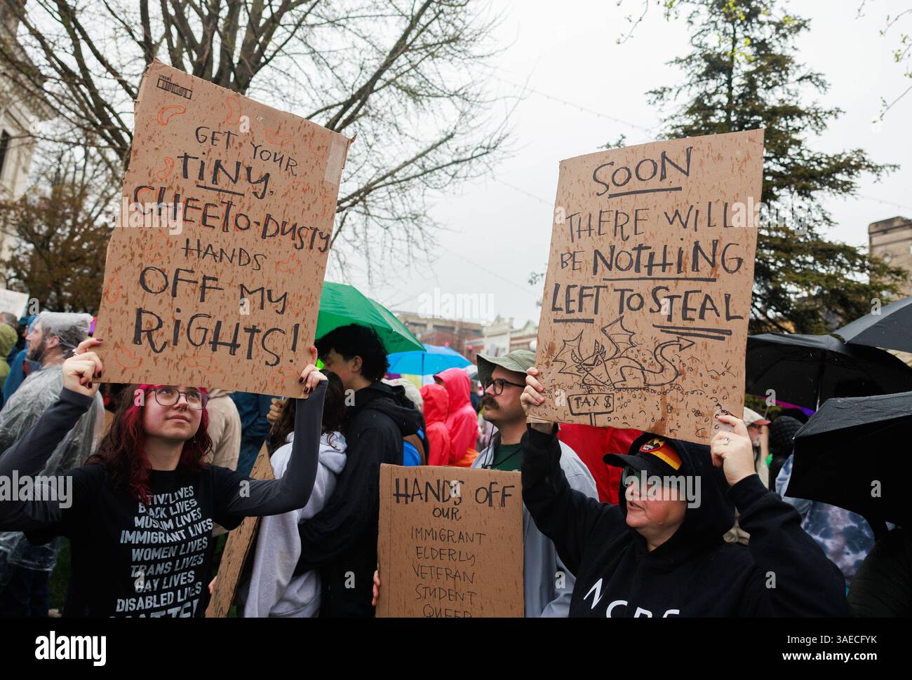 A woman carries a placard reading, “Get your tiny Cheeto-Dusty hand off ...