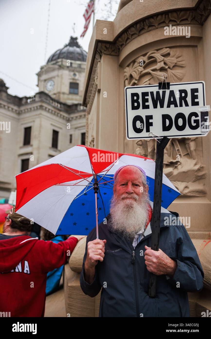 A protester holds a placard reading, “Beware of DOGE” during the rally ...