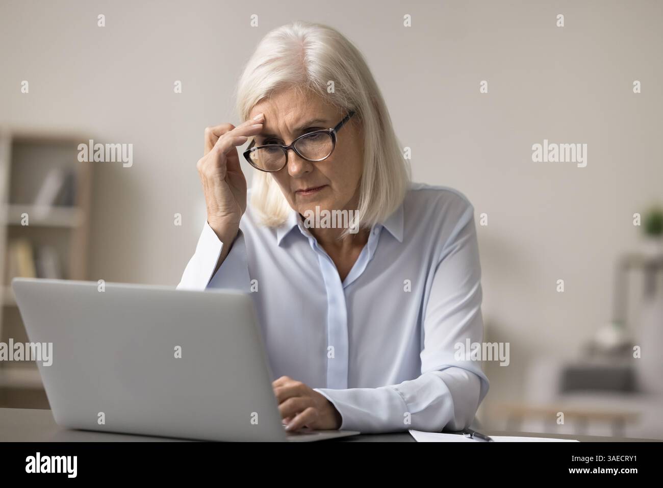 Concerned senior lady accountant sit at office desk by notebook Stock ...