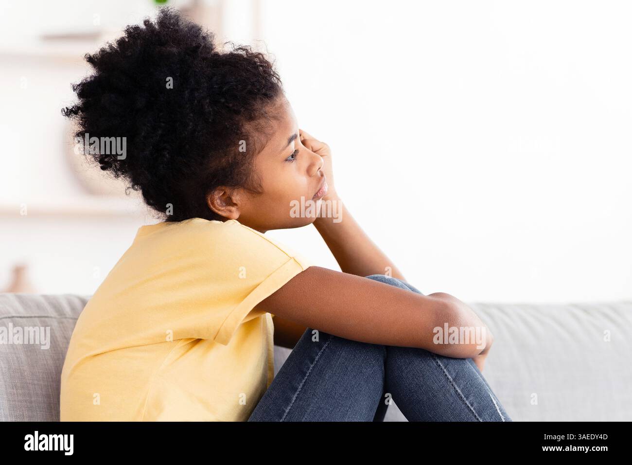 Unhappy Black Kid Girl Sitting On Couch At Home Alone Stock Photo - Alamy