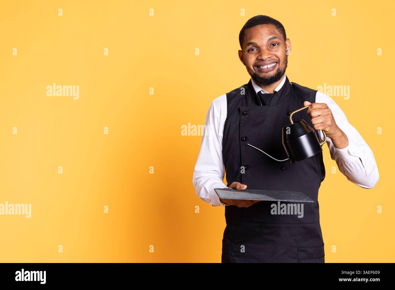Skilled waiter bringing the teapot to the clients table to serve them ...