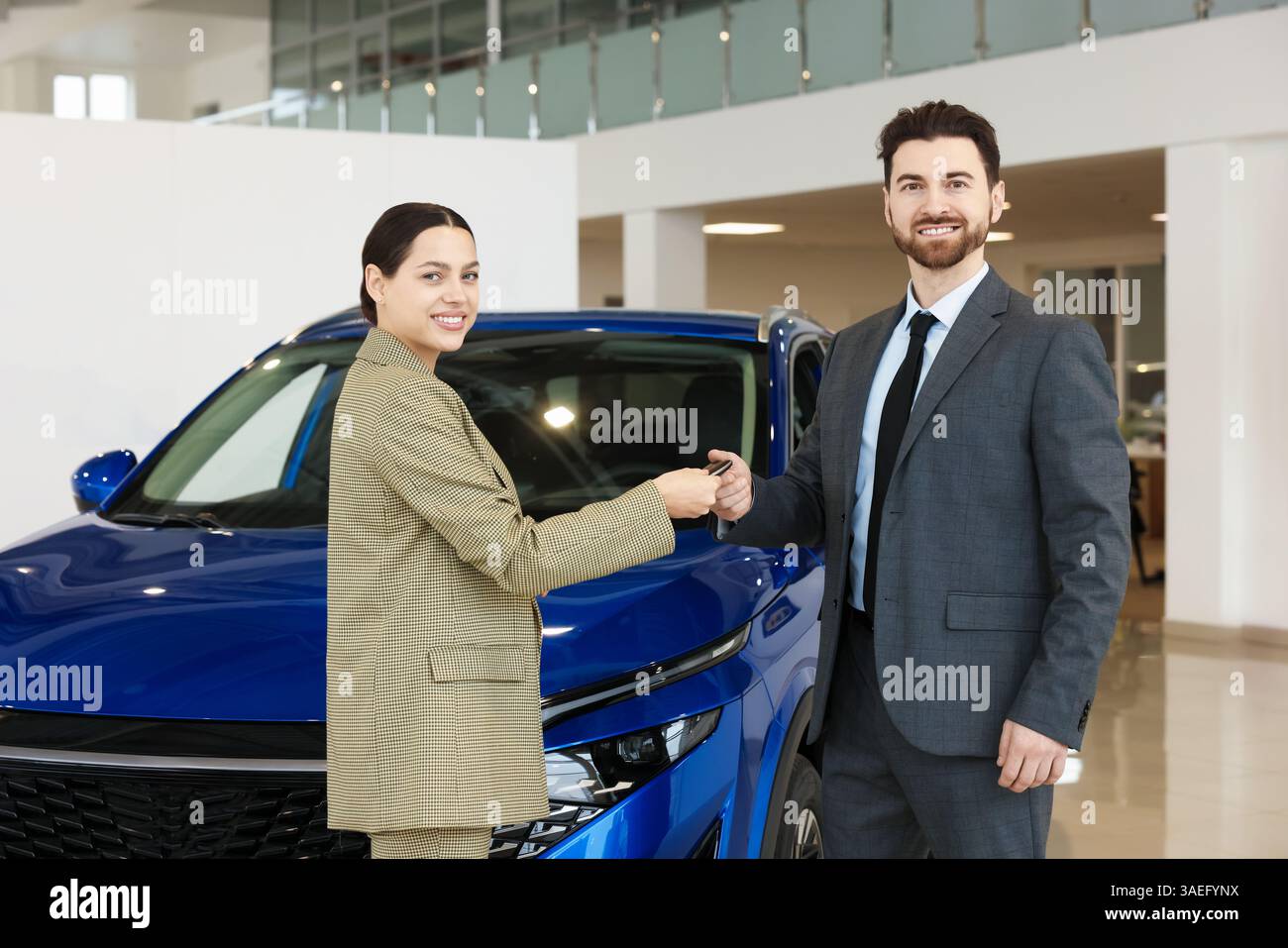 Happy saleswoman giving car key to client in salon Stock Photo - Alamy