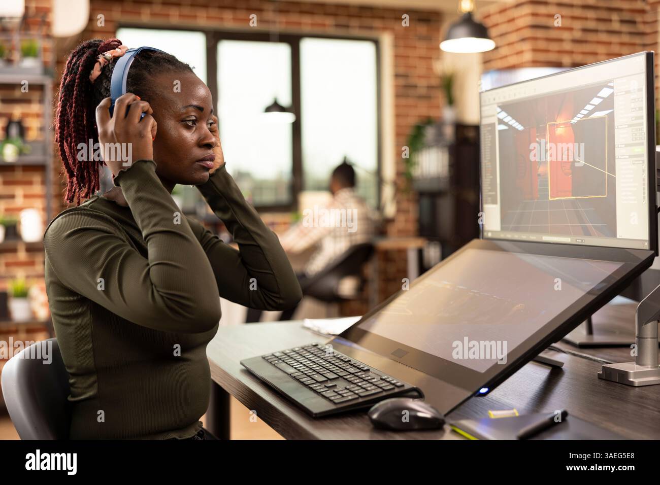 African American designer refining projects on digital monitors ...