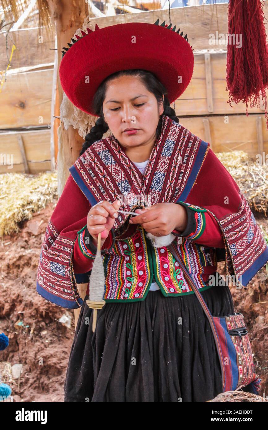 Peruvian woman in traditional clothes in Chinchero village textil craft shop showing tourists ...