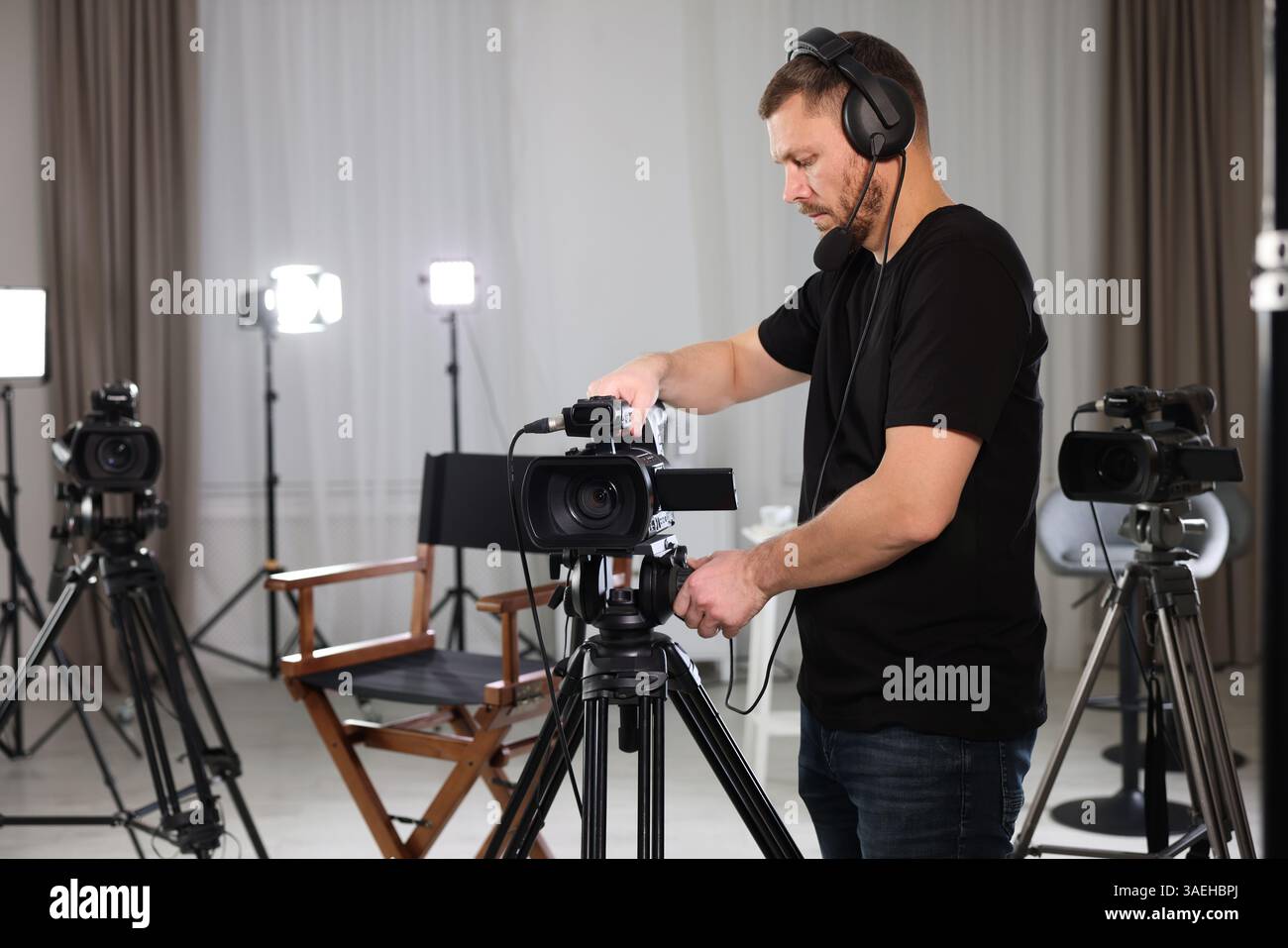 Cameraman with camera and headphones in film studio Stock Photo - Alamy