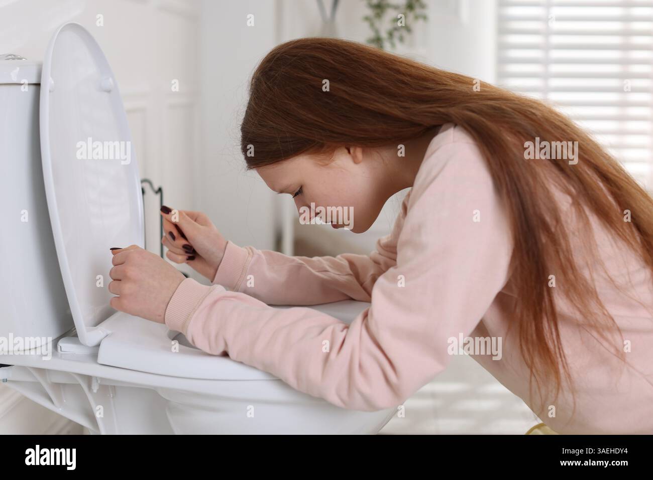 Teenage girl suffering from nausea over toilet bowl in bathroom ...