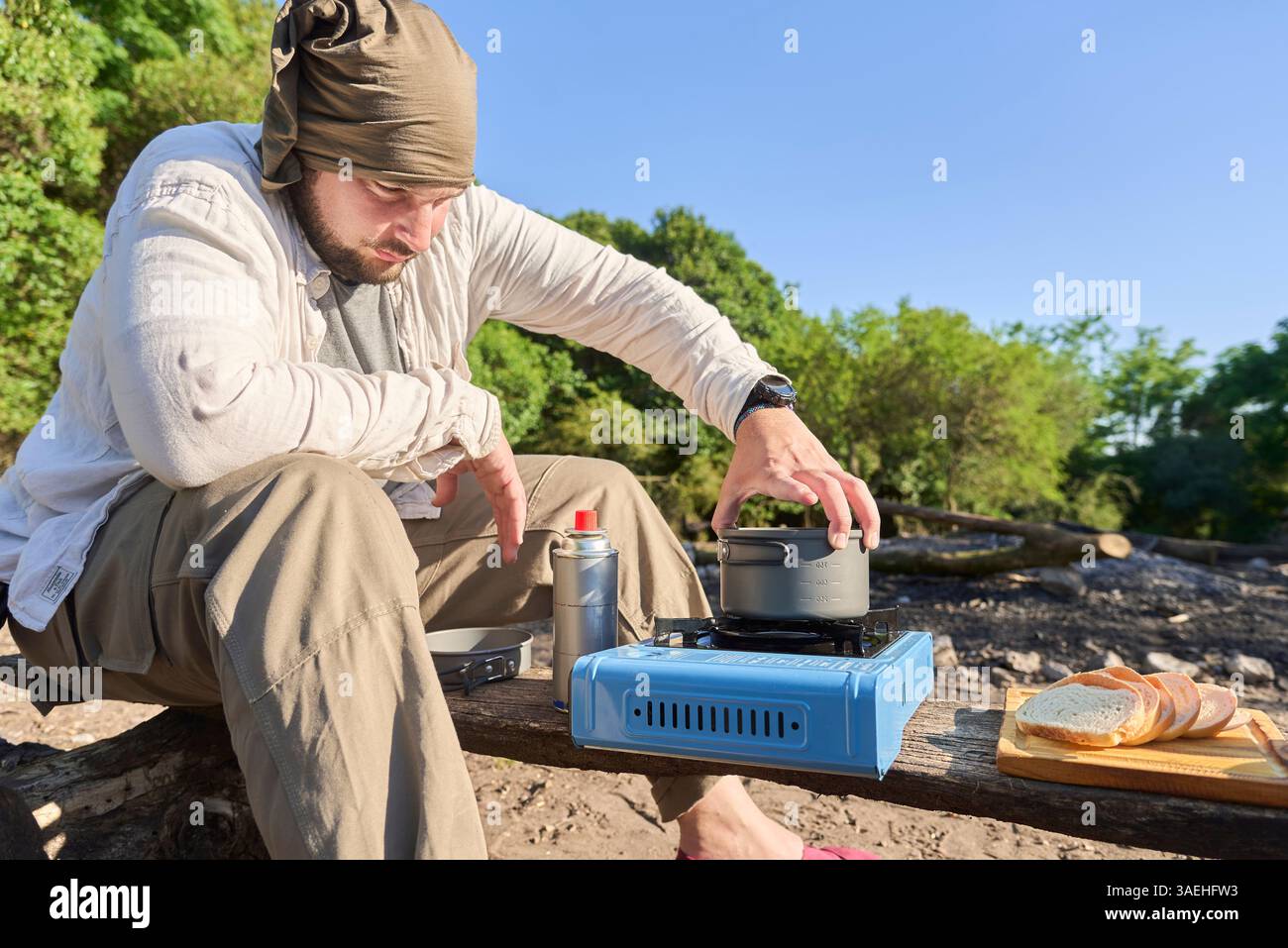 Hispanic man cooking outdoors on a light blue portable stove while ...
