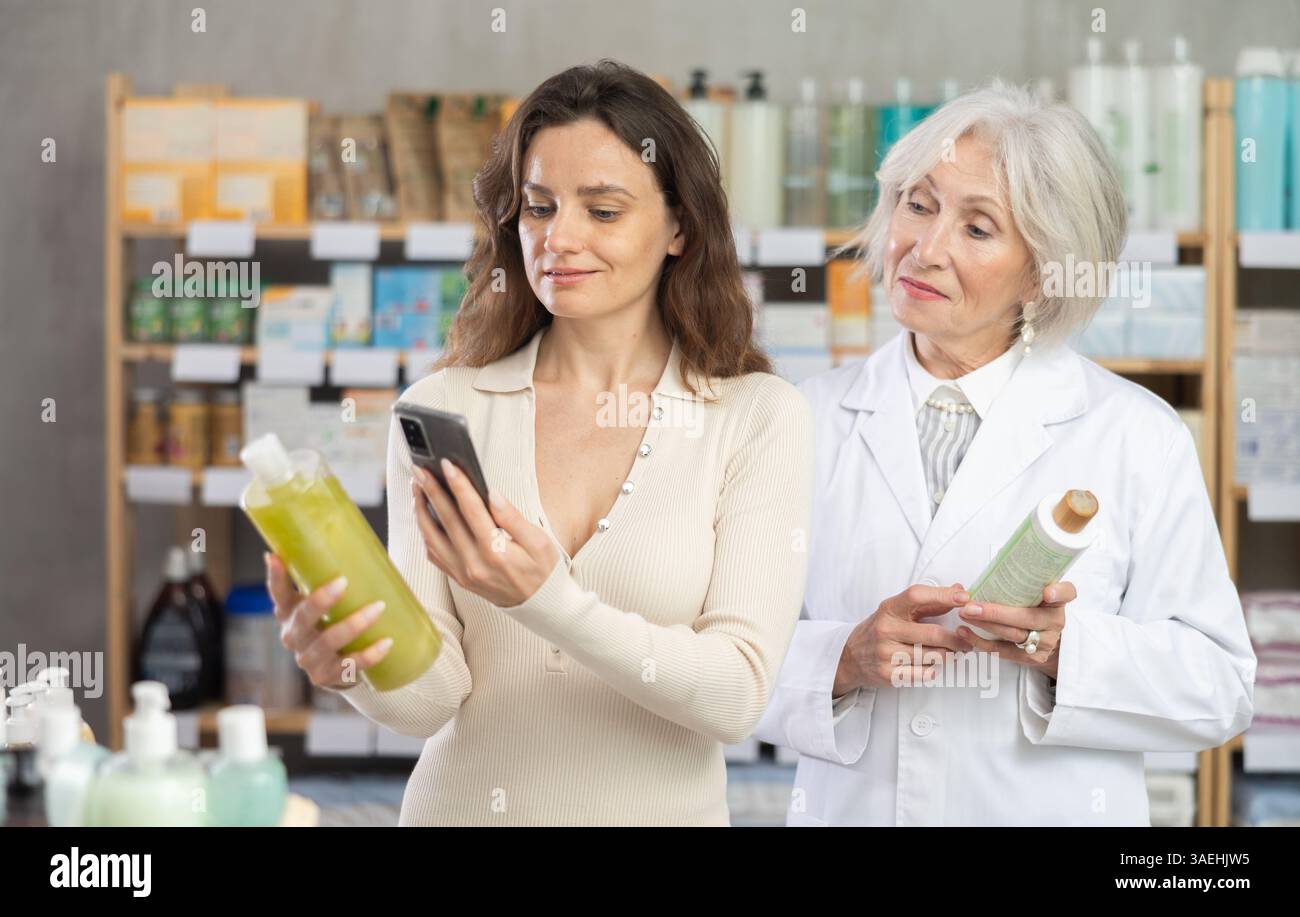 Adult European woman scans shampoo barcode in front of pharmacist Stock ...