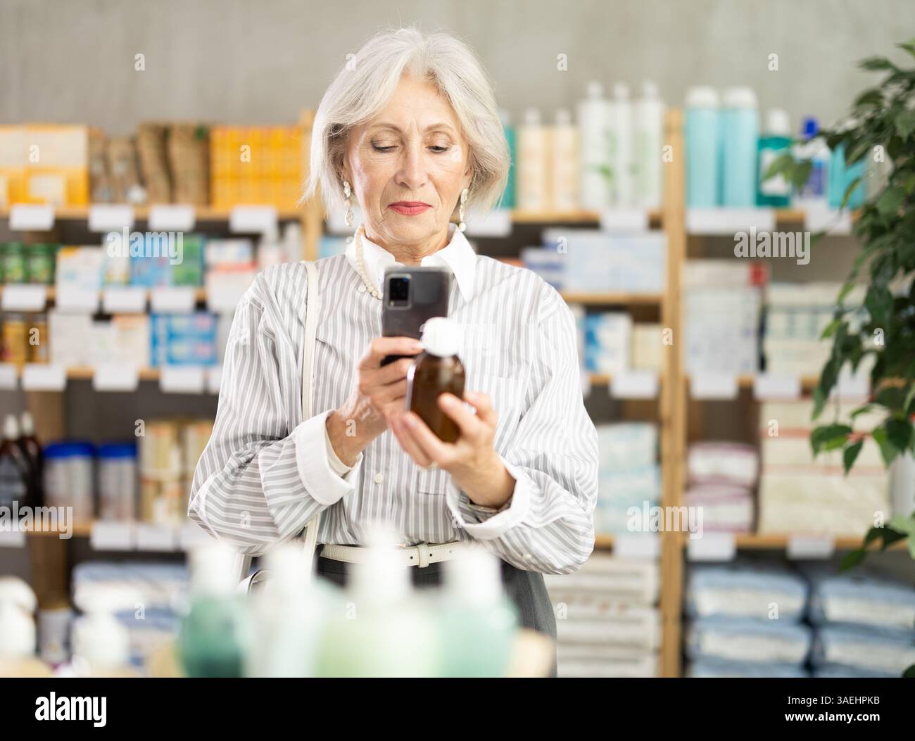 Elderly woman scanning qr code of syrup Stock Photo - Alamy