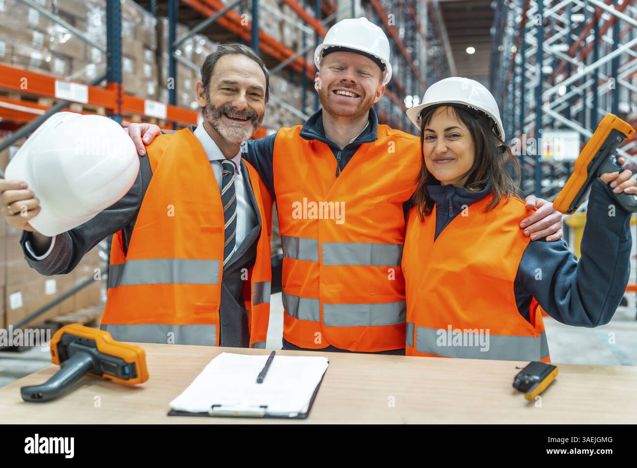 Warehouse workers and their manager are smiling and hugging each other ...