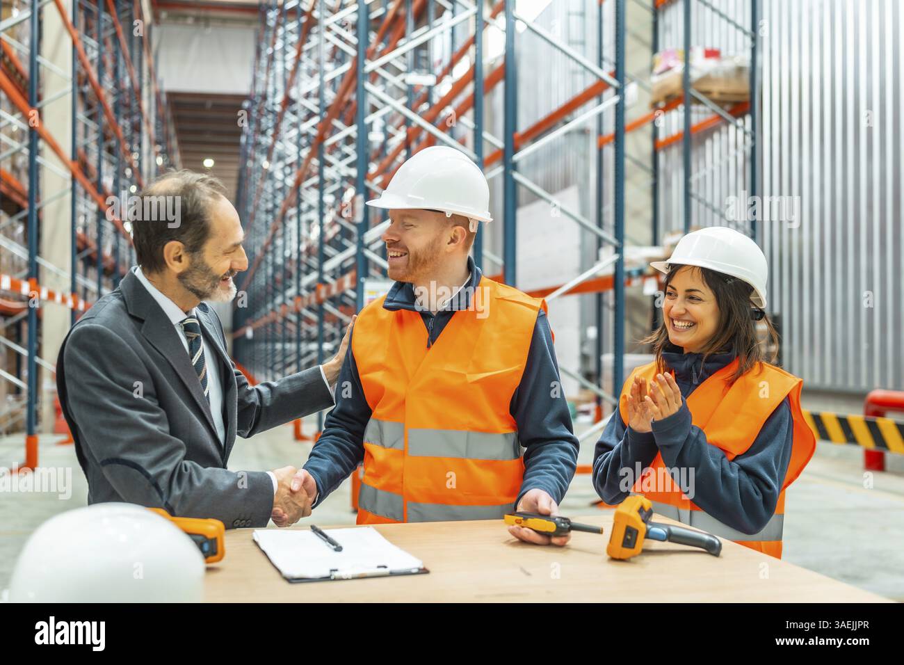 Manager shaking hands with a warehouse worker after closing a deal, his ...