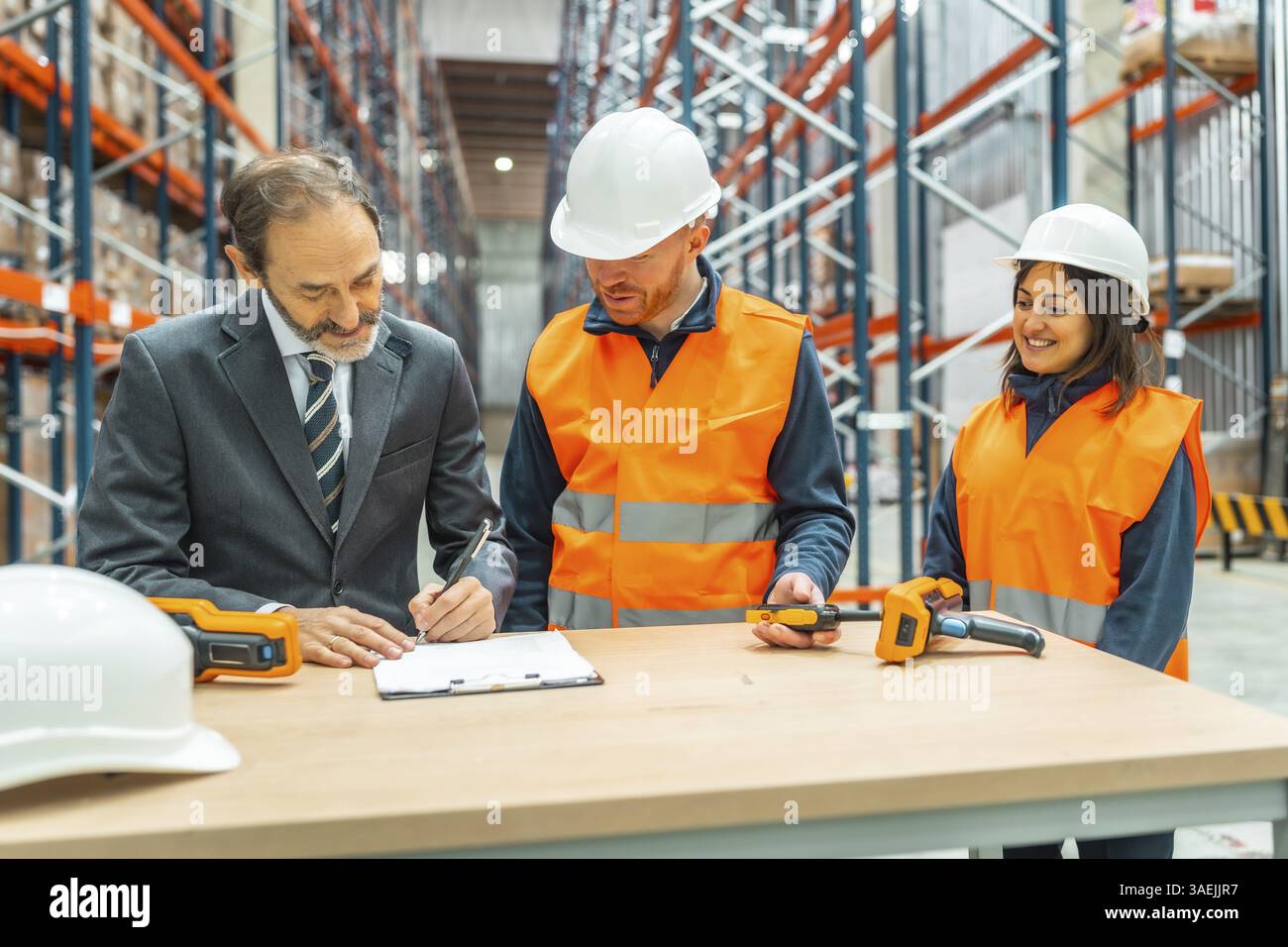 Manager signing delivery notes in a logistics warehouse, assisted by ...