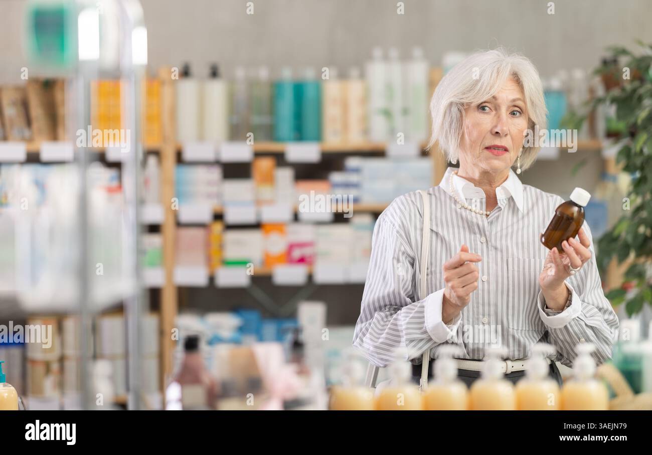 Elderly woman chooses syrup at pharmacy Stock Photo - Alamy