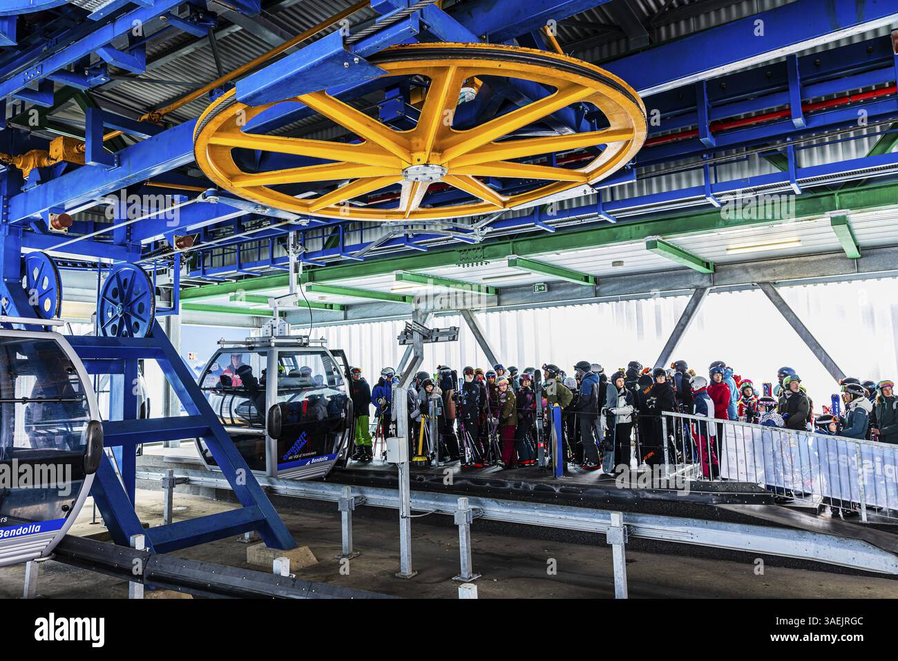 Skiers queue at the valley station for the ascent with the cable car to ...