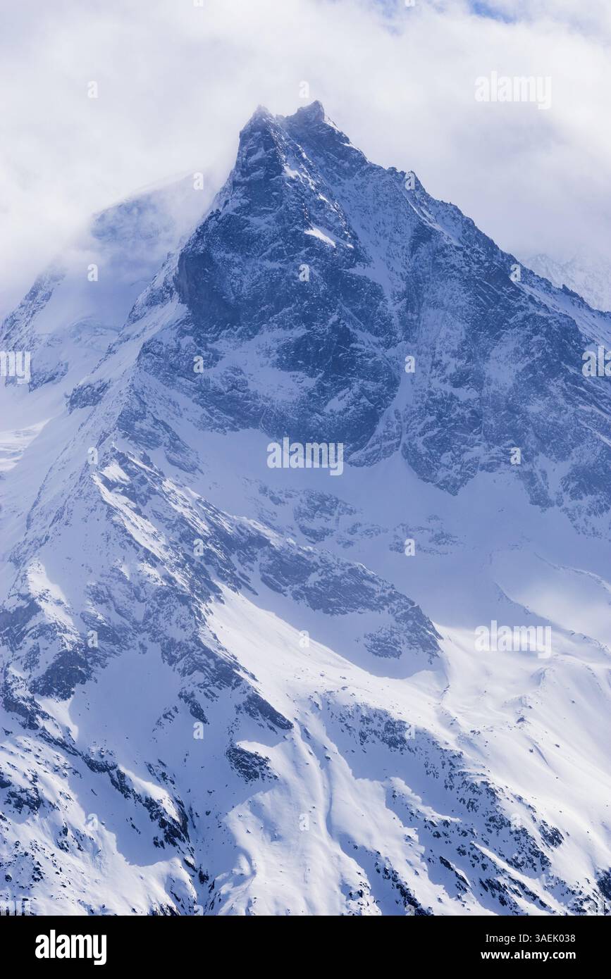 Fog envelops the snowy summit of the mountain Le Besso, Val d'Anniviers ...