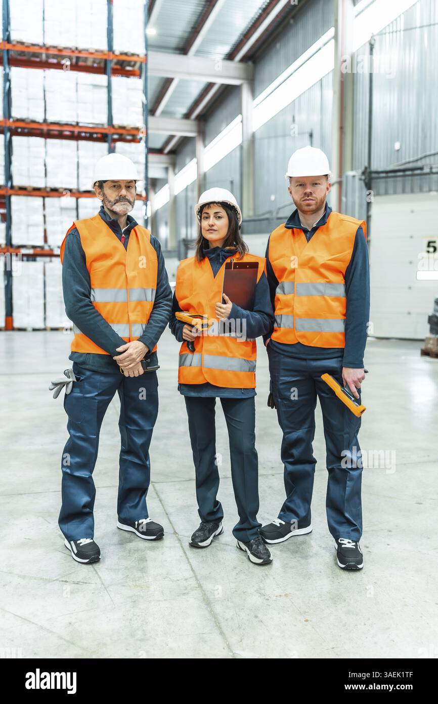 Warehouse workers wearing safety vests and helmets managing inventory ...