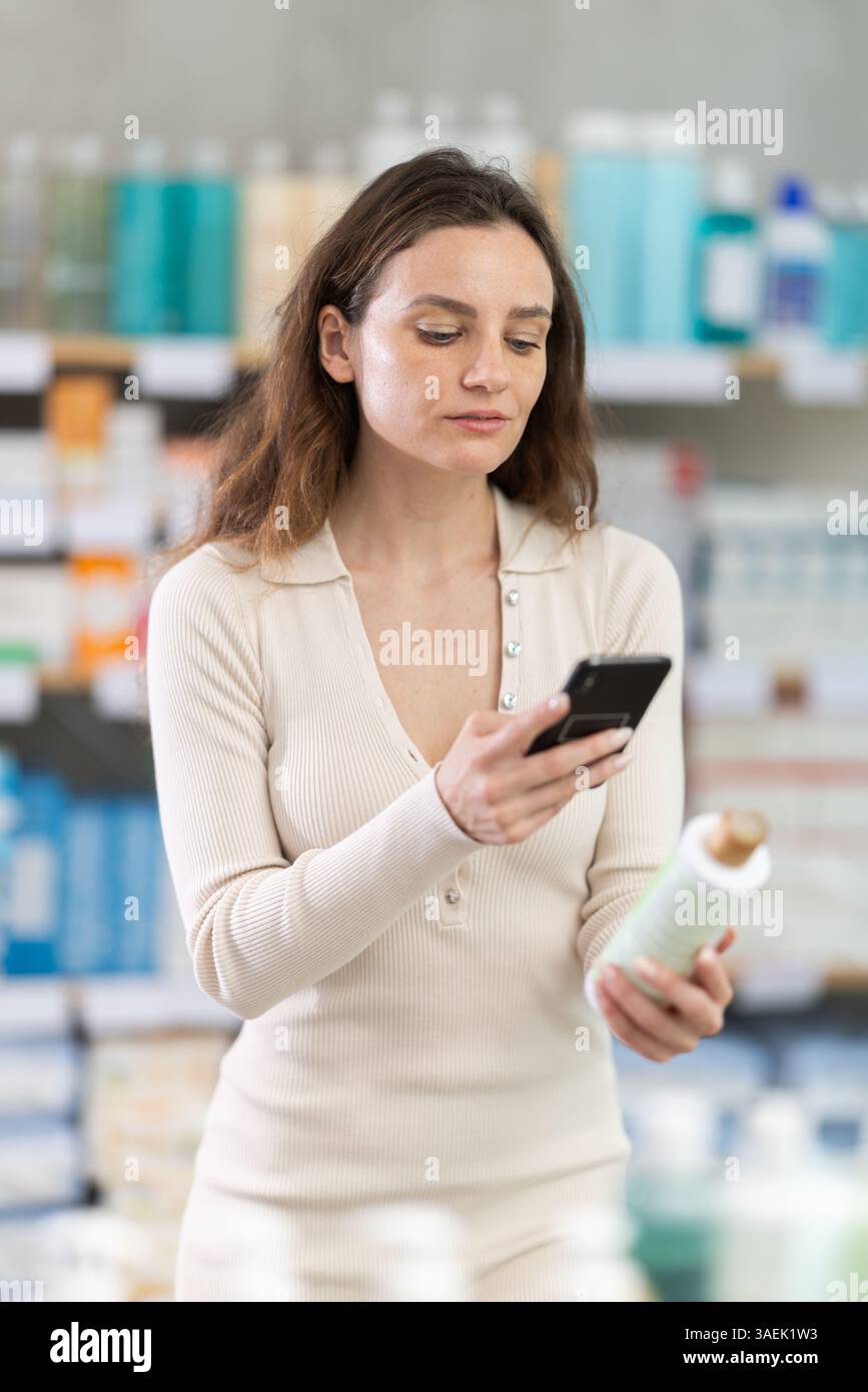 Woman in pharmacy scans QR code on shampoo product Stock Photo - Alamy