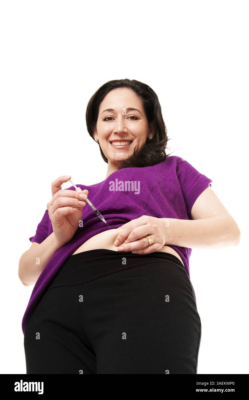 Attractive happy diabetic woman injecting insulin in her belly for ...