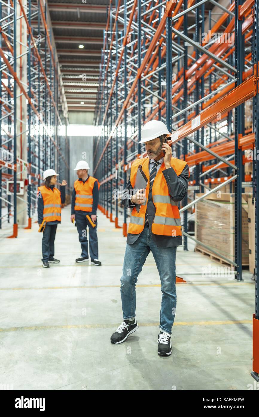 Manager coordinating logistics operations using phone and holding ...