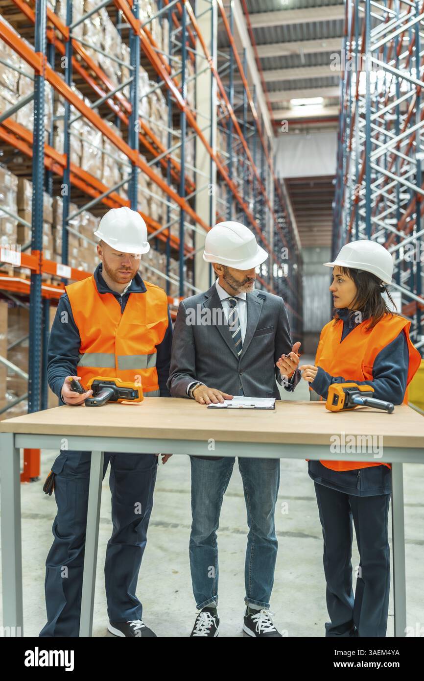 Warehouse workers and manager discussing logistics while using barcode ...
