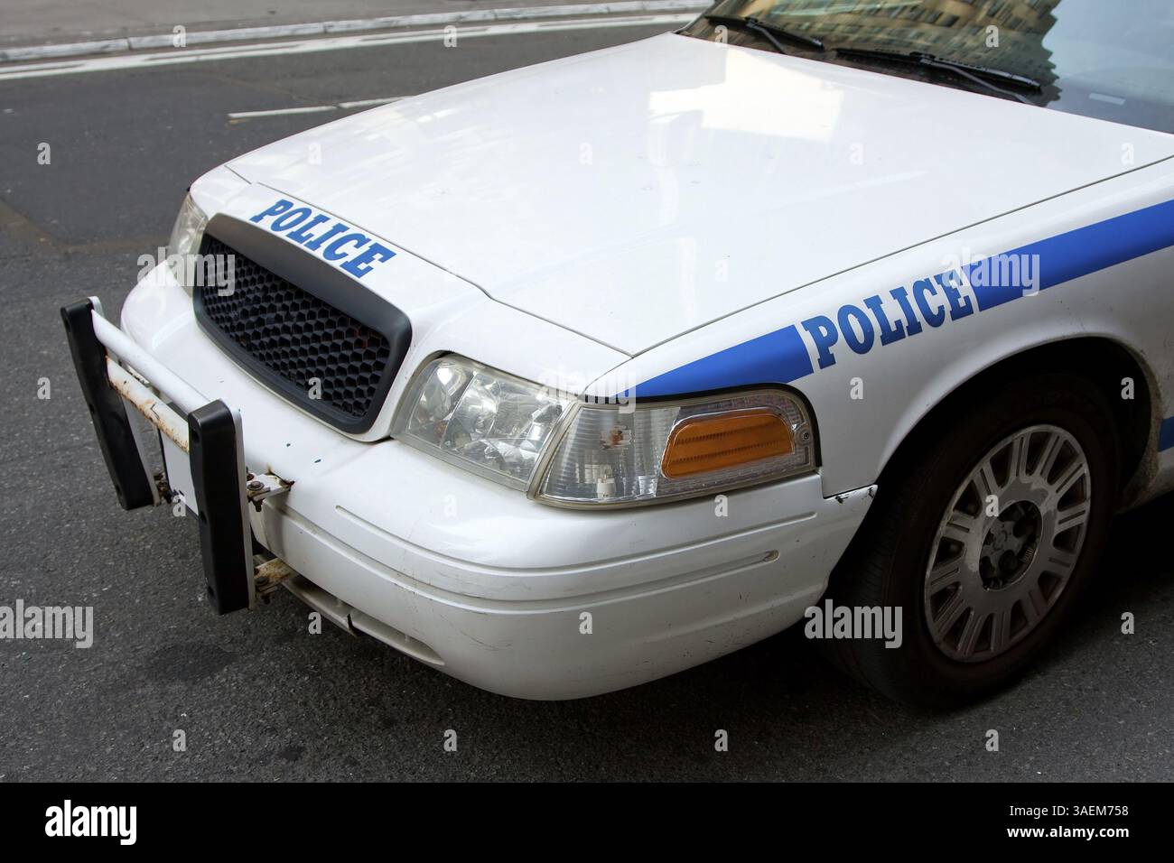 Front and side view of a white police car with blue letters saying ...